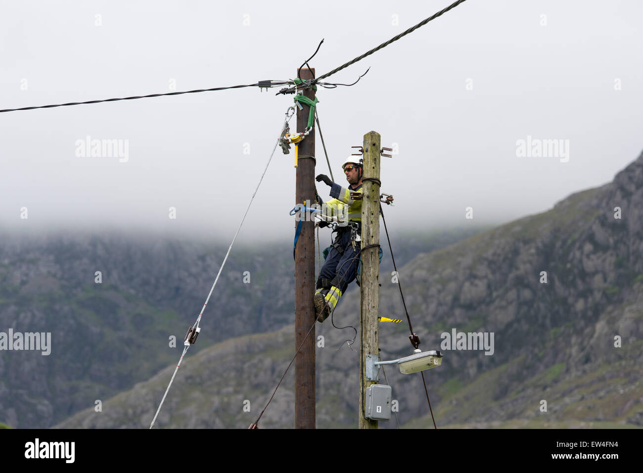 An engineer carries out maintenance on a electricity utility pole in ...