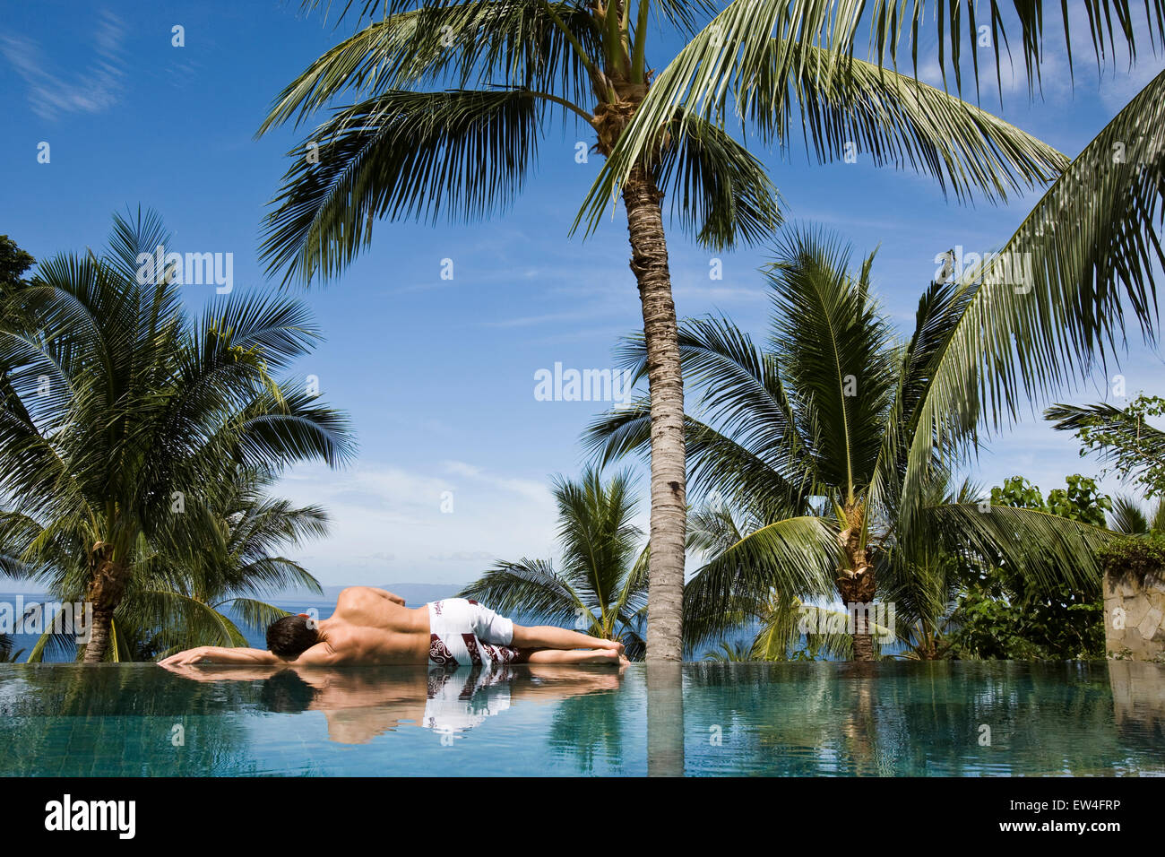 Man sitting under palm tree hi-res stock photography and images - Alamy