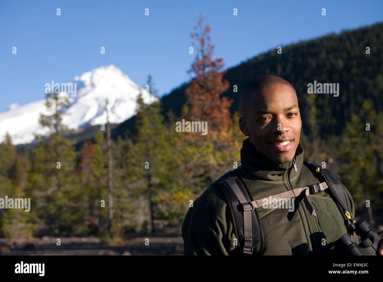 African American man Cupid Alexander stands with binoculars in forest ...