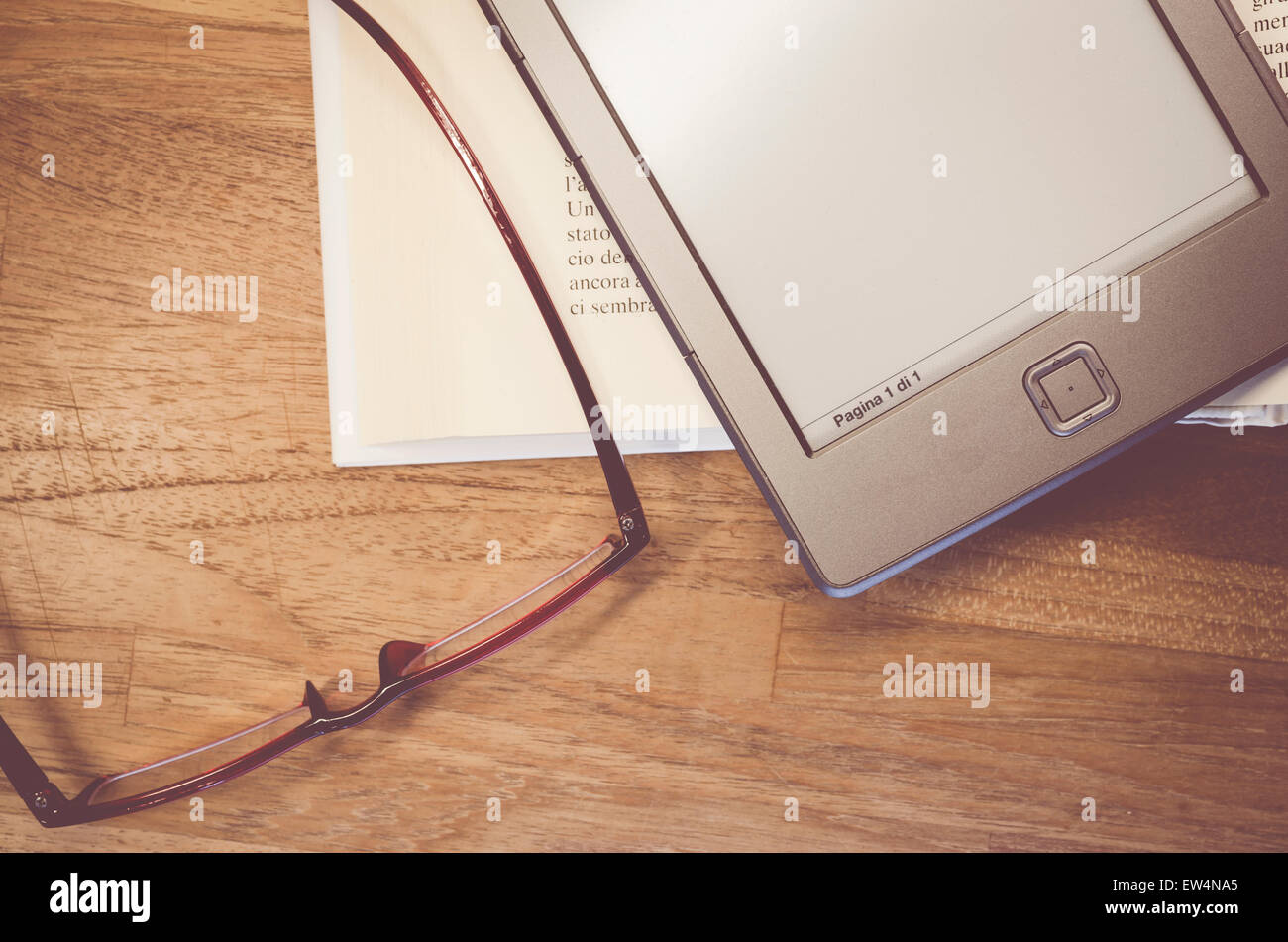 electronic reading device open book and reading glasses on a natural ...