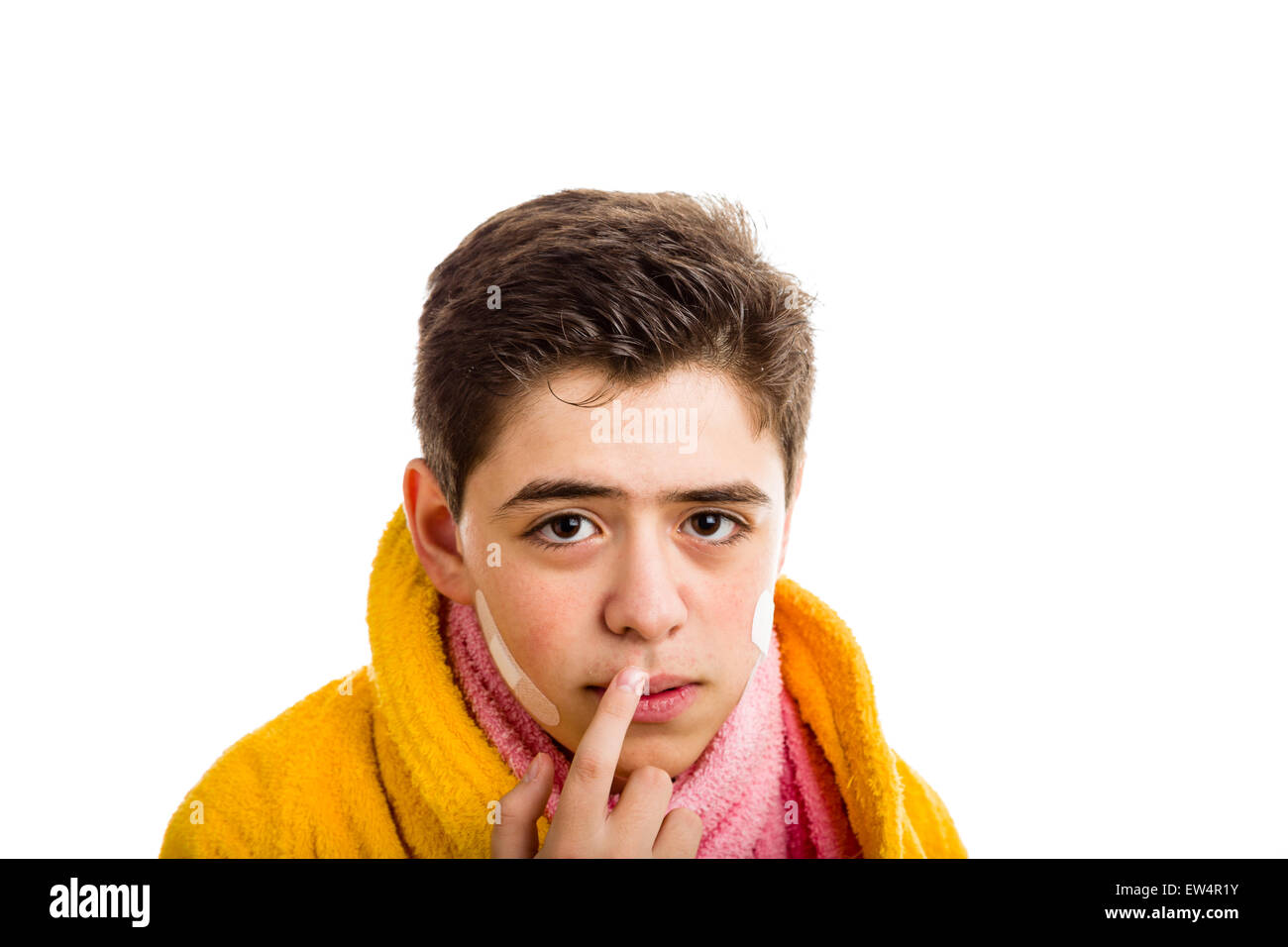 A Caucasian boy is touching his cuts with finger after shaving wearing ...