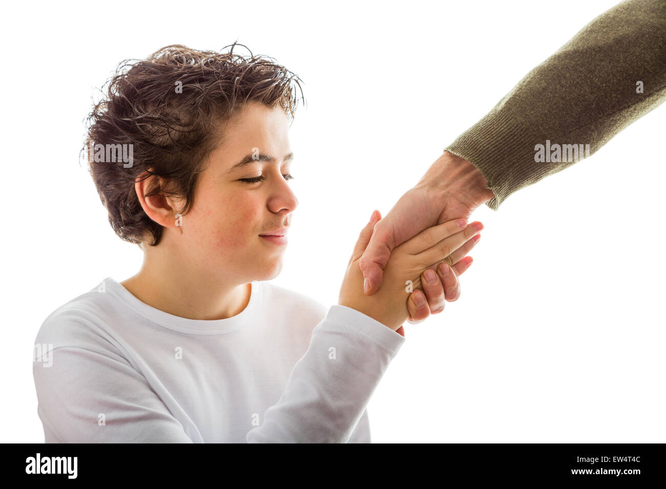A Caucasian boy smiles shaking hands with adult from his left side ...