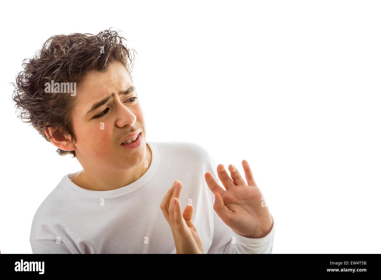 Worried Hispanic boy with disheveled hair in white long sleeved t-shirt ...