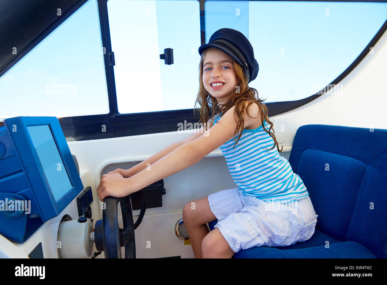 Kid girl pretending be a captain sailor cap in boat indoor holding ...