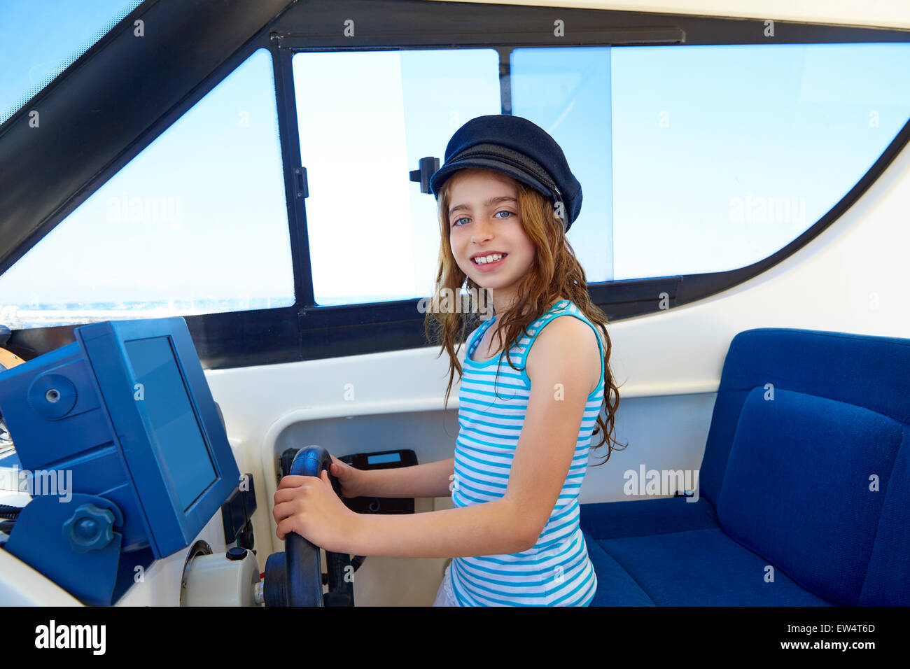 Kid girl pretending be a captain sailor cap in boat indoor holding ...