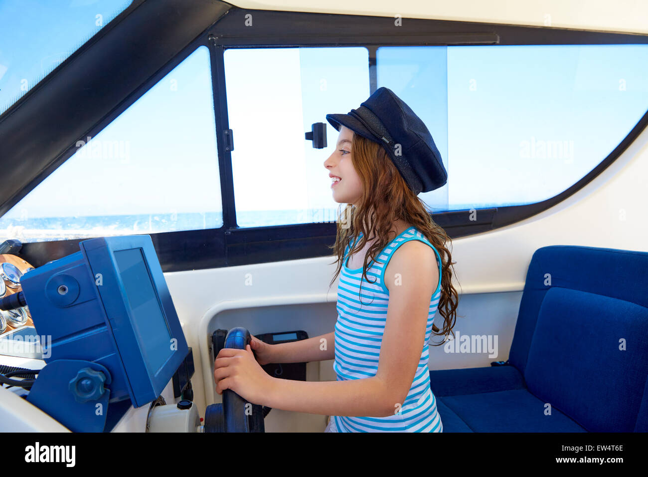 Kid girl pretending be a captain sailor cap in boat indoor holding ...