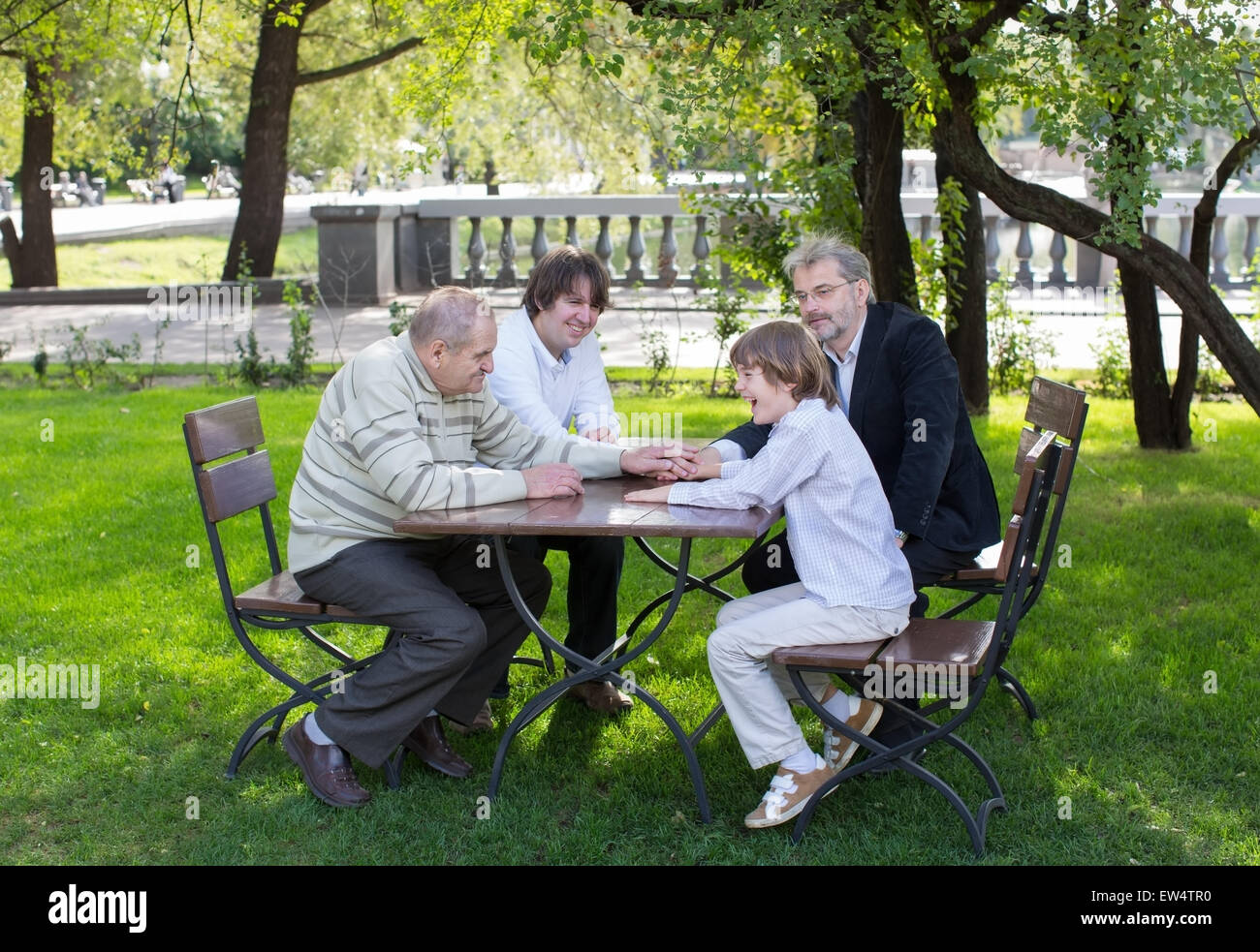 Four generations of one family sitting at a wooden table in the garden ...