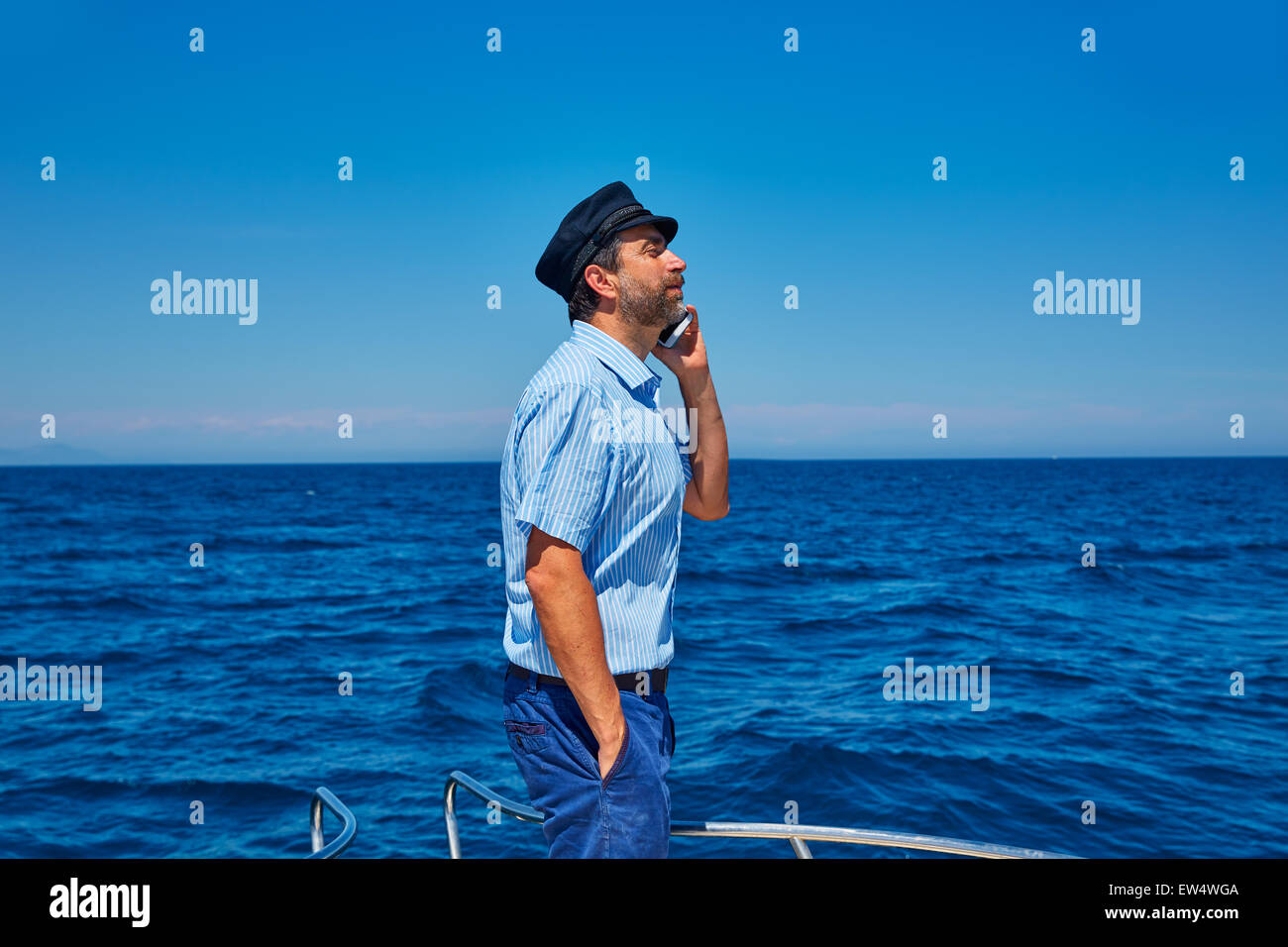 Captain cap sailor man talking mobile phone in boat sailng in the ocean ...