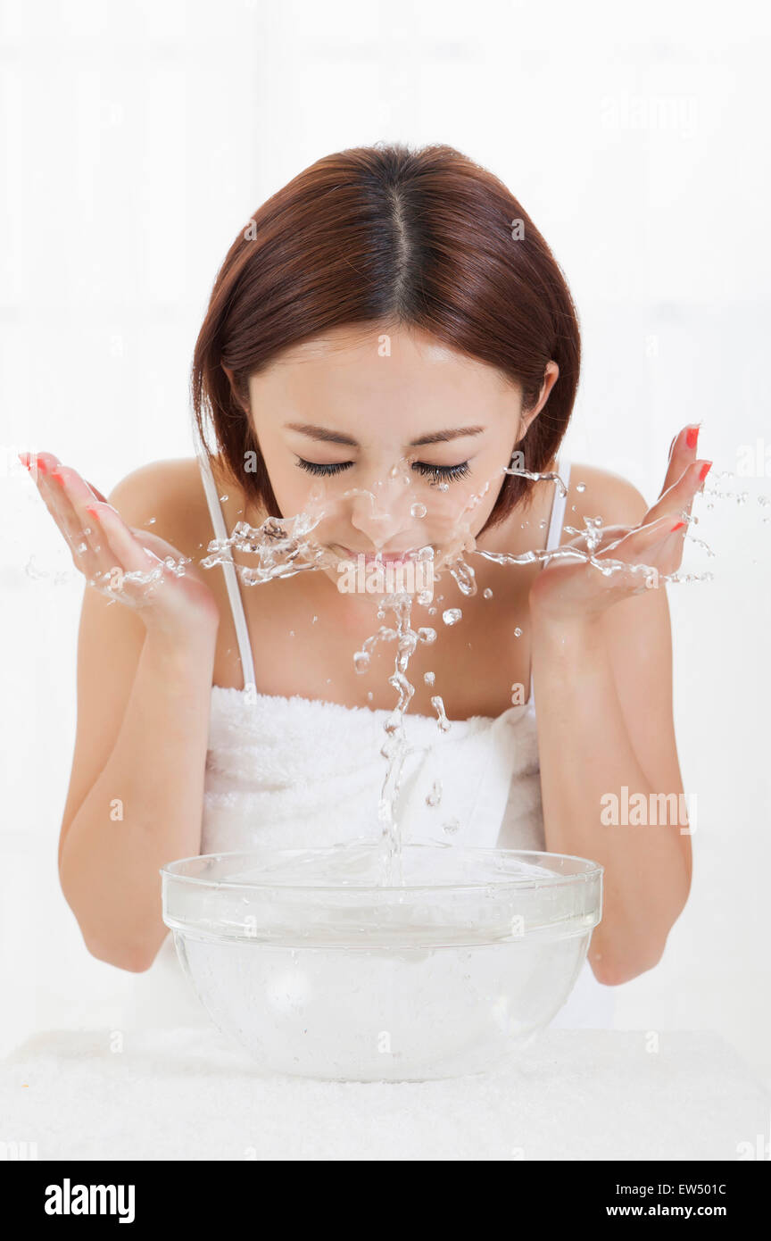 Young woman washing face with eyes closed Stock Photo - Alamy
