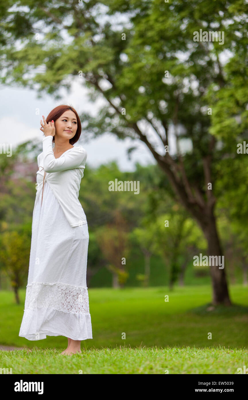 Young woman standing with hand in hair Stock Photo - Alamy