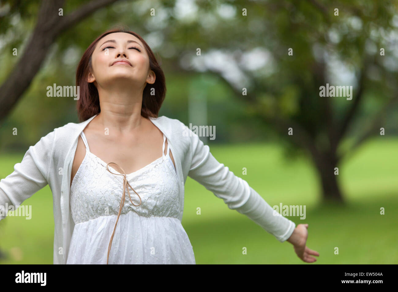 Young woman closing eyes with arms outstretched Stock Photo - Alamy