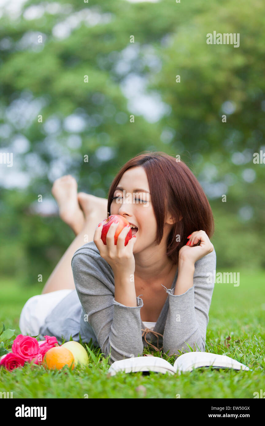 Young woman lying down on front and eating an apple Stock Photo - Alamy