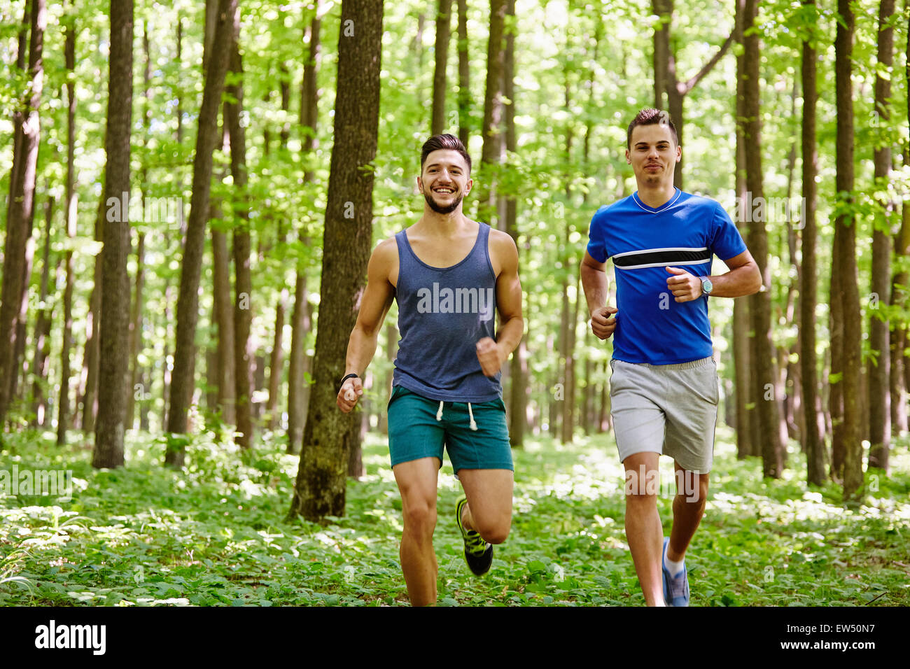 Two friends running through the forest on a jogging trail Stock Photo ...