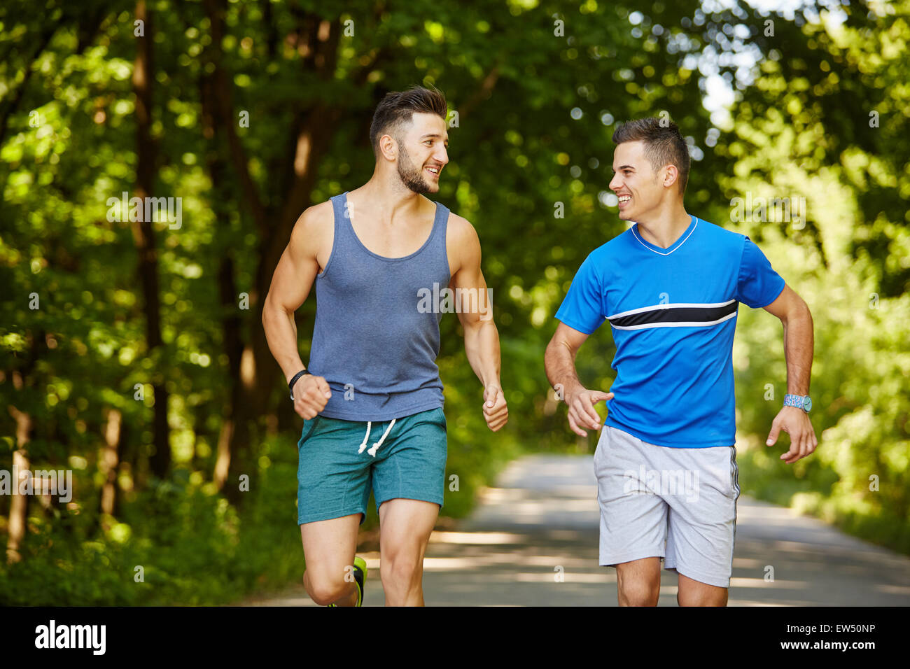 Two friends running through the forest on a jogging trail Stock Photo ...