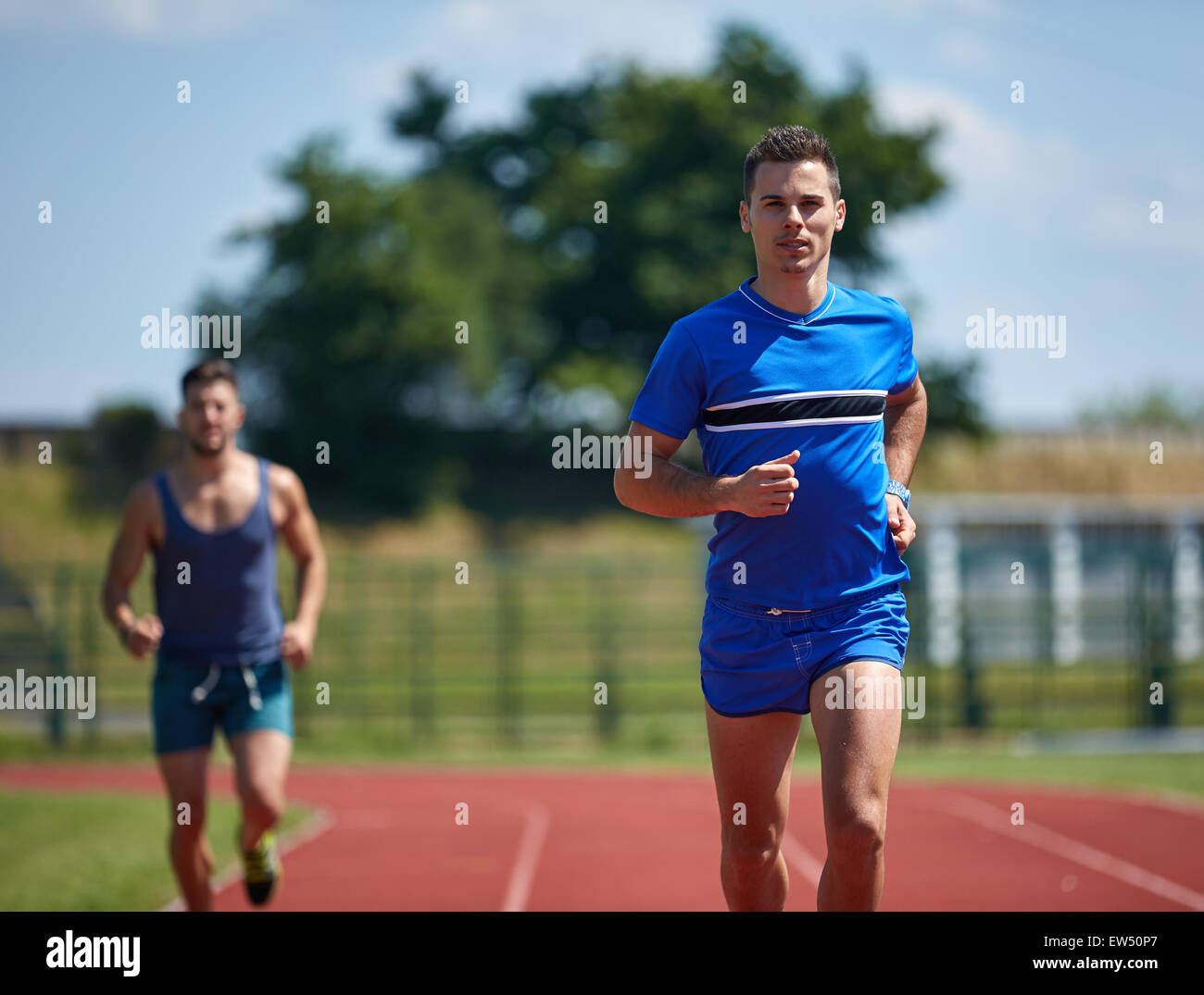 Two friends running on the lines at the stadium in a sunny day Stock ...