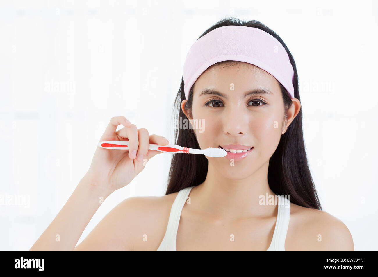 Young woman brushing teeth with smile Stock Photo - Alamy