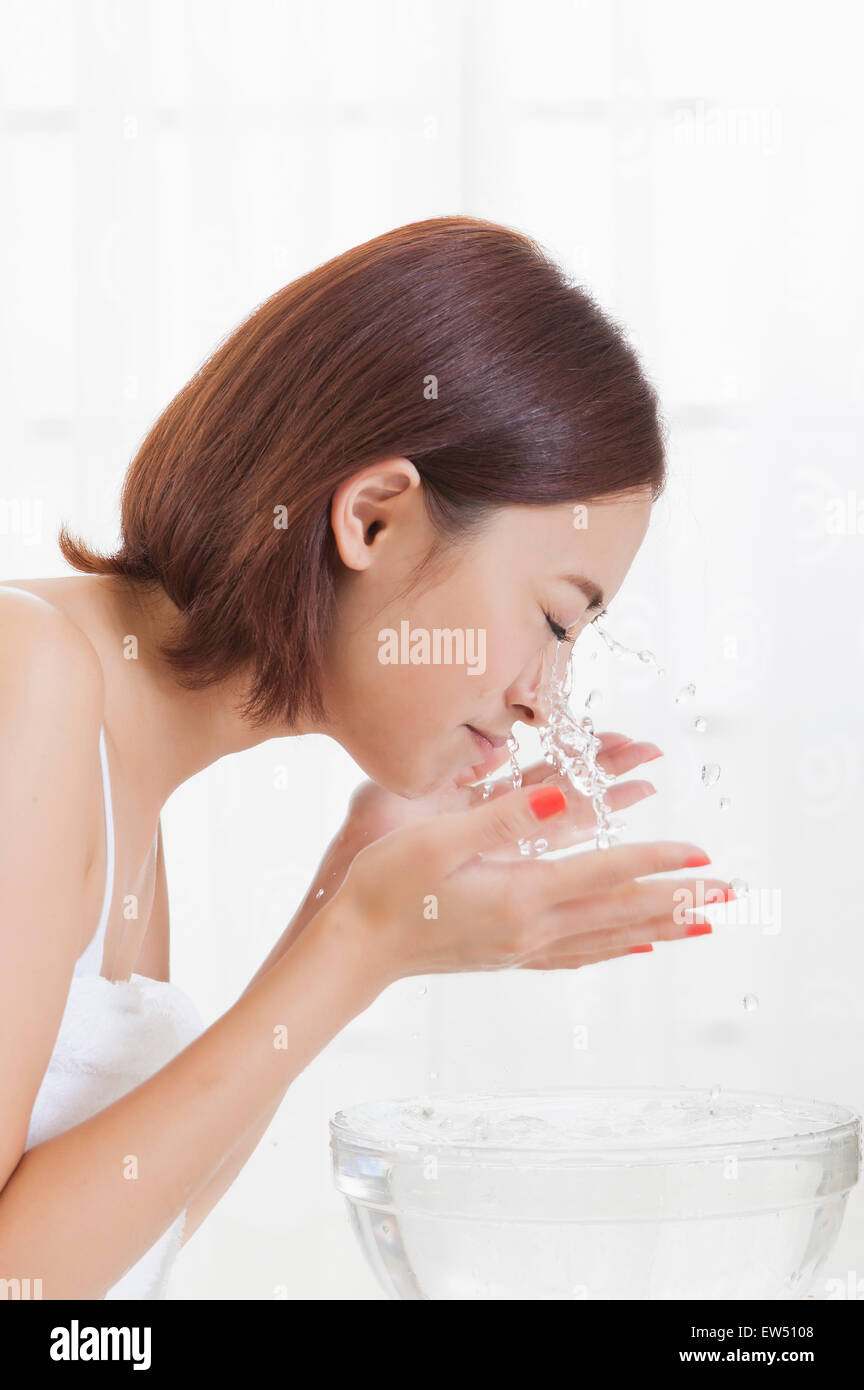 Young woman washing face with eyes closed Stock Photo - Alamy