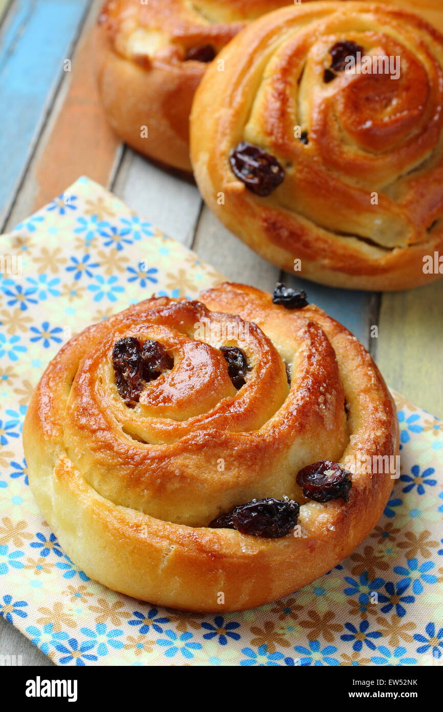 Fresh sweet swirl buns with raisins on colored wooden table Stock Photo ...