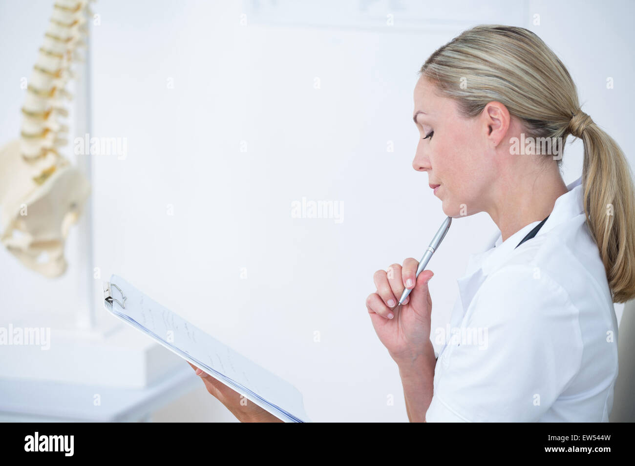 Doctor writing on clipboard at her desk Stock Photo - Alamy