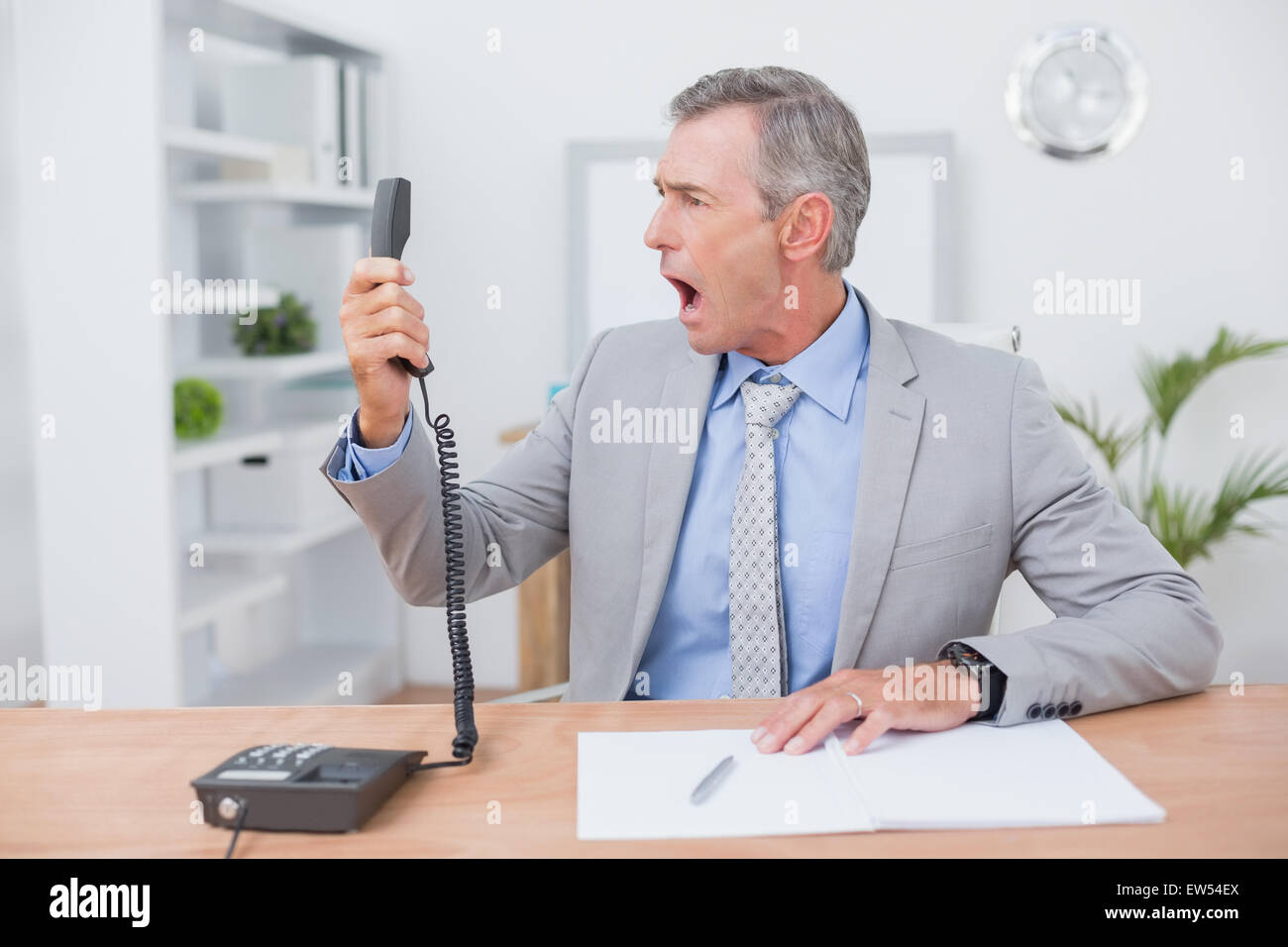 Irritated businessman answering phone Stock Photo - Alamy
