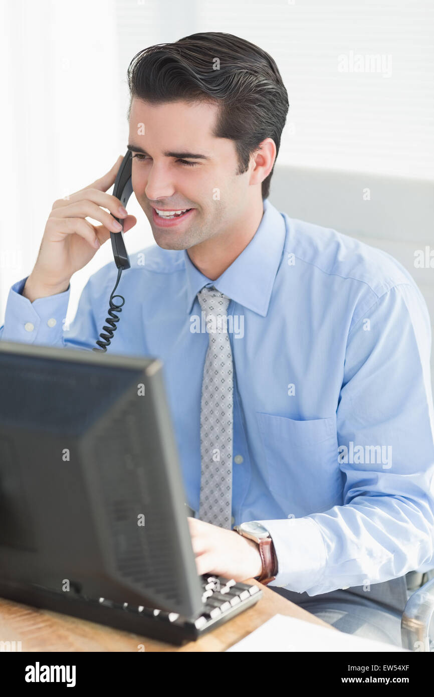 Businessman having phone call while using his laptop Stock Photo - Alamy