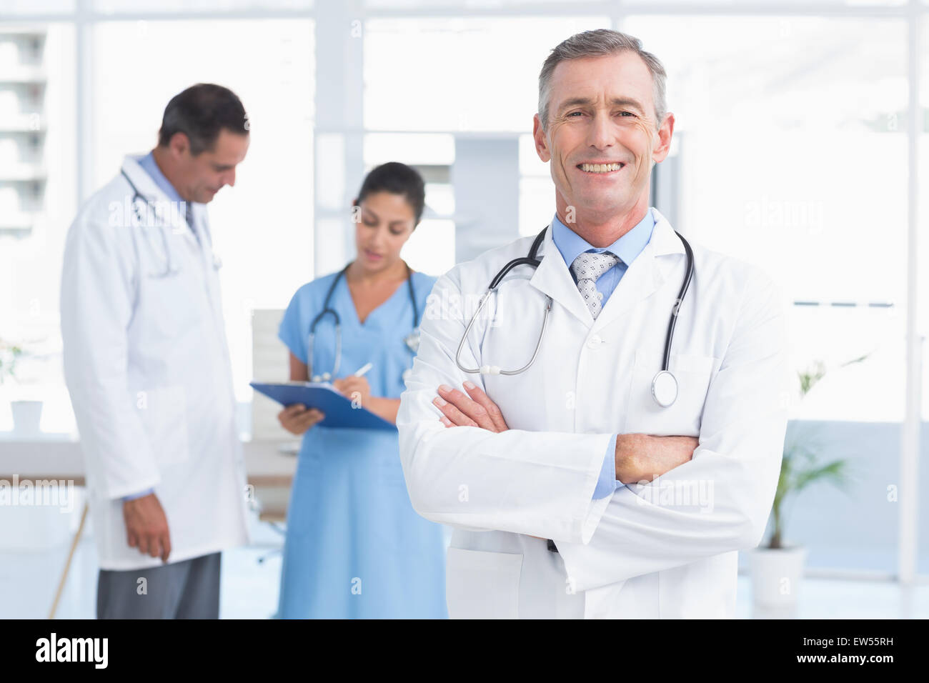Doctor looking at camera while his colleagues works Stock Photo - Alamy