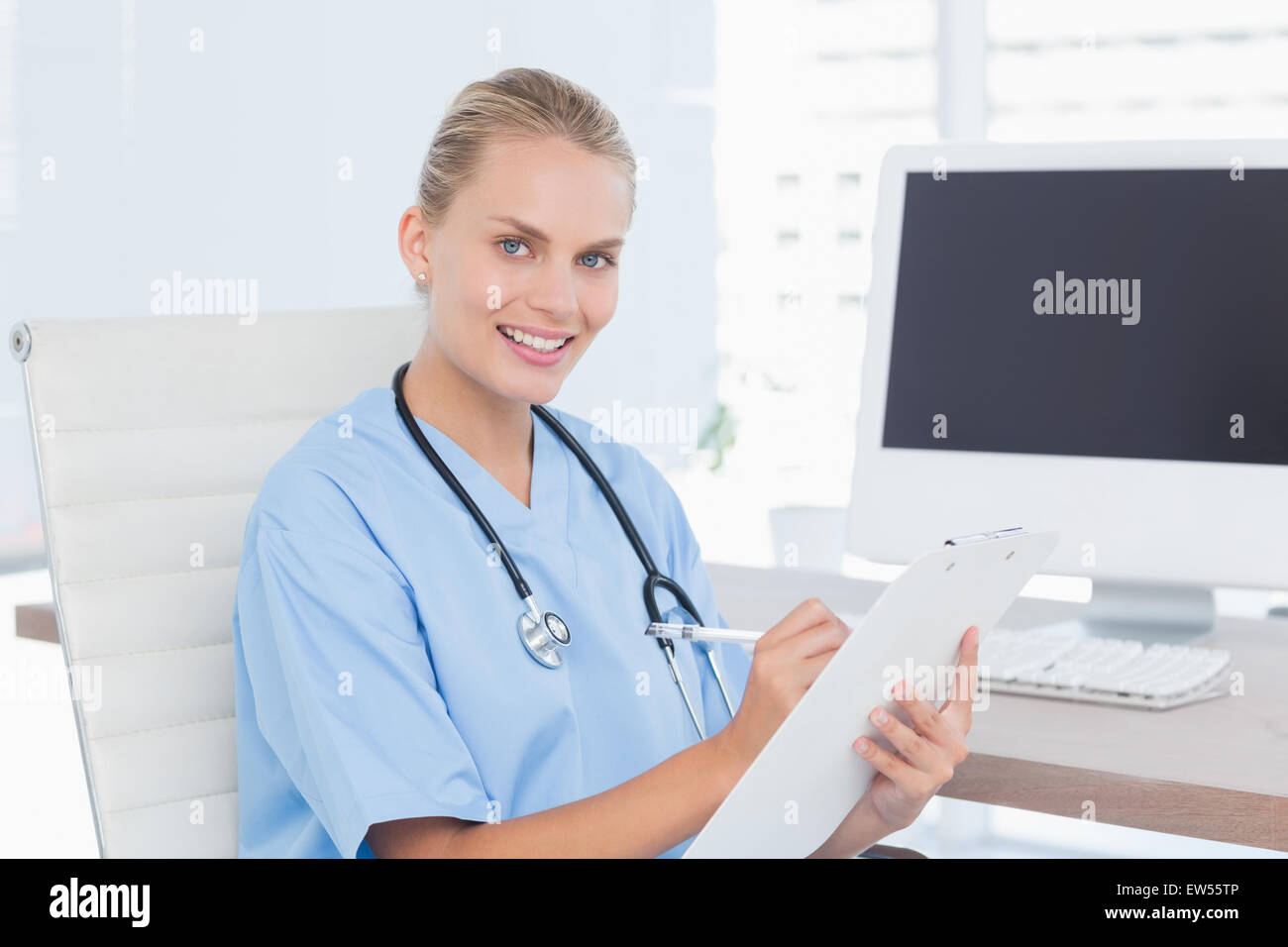 Concentrated nurse writing on clipboard Stock Photo - Alamy