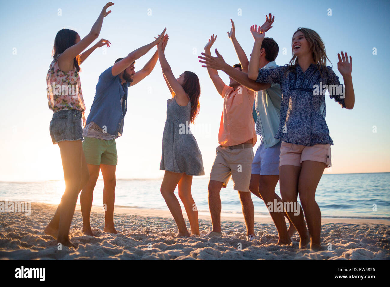 Happy friends dancing on the sand Stock Photo - Alamy