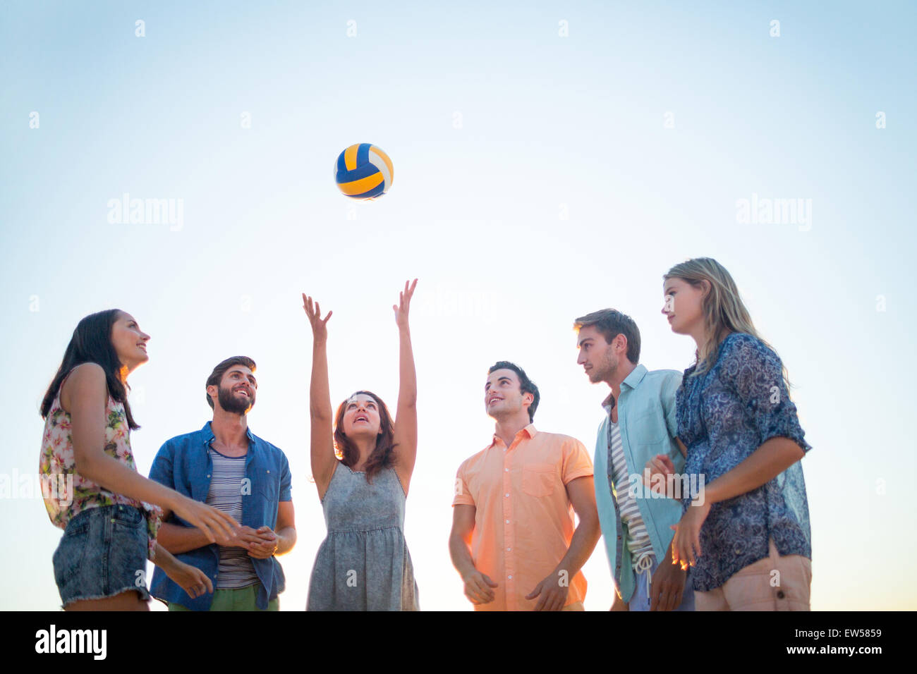 Happy friends throwing volleyball Stock Photo - Alamy