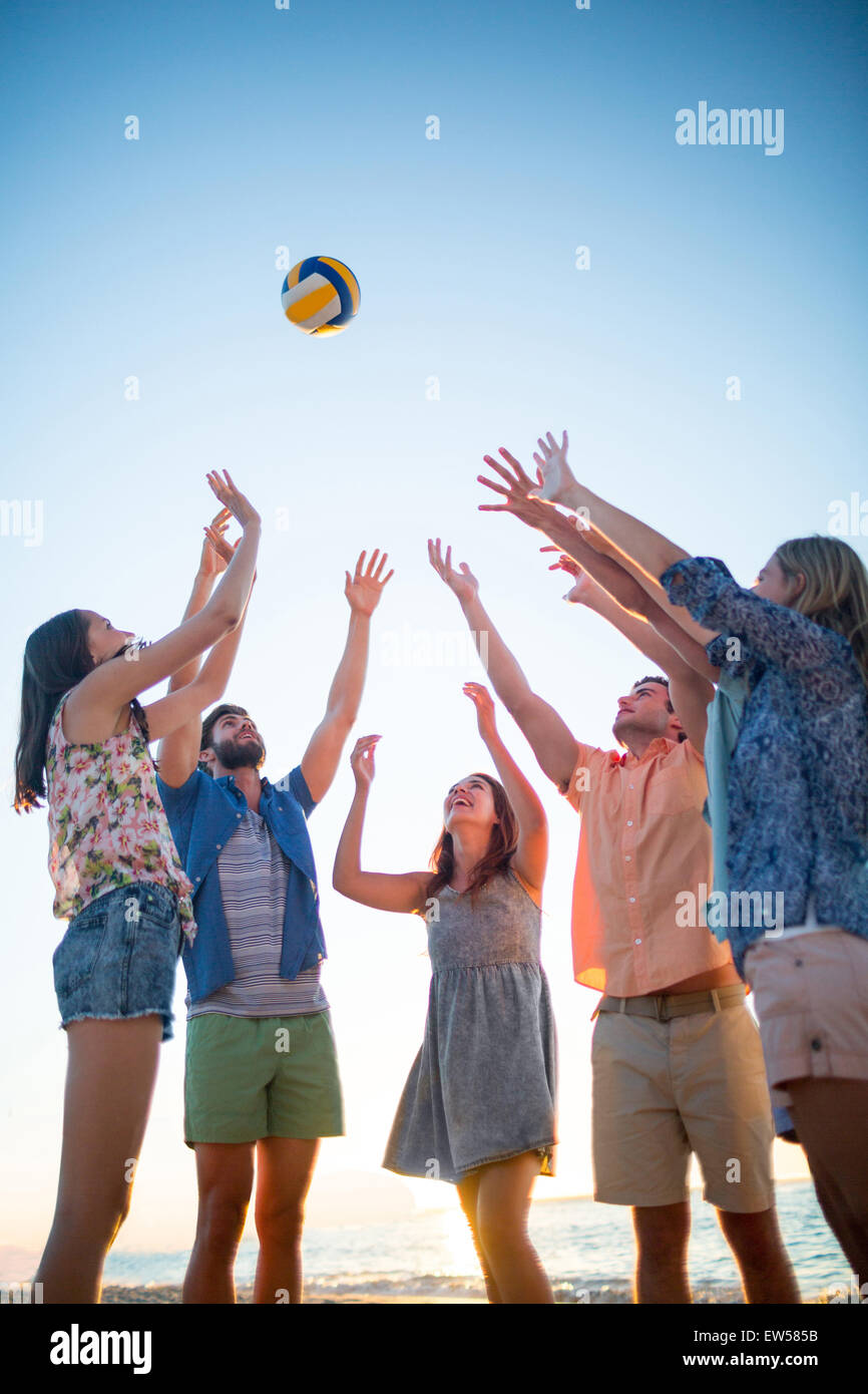 Happy friends throwing volleyball Stock Photo - Alamy