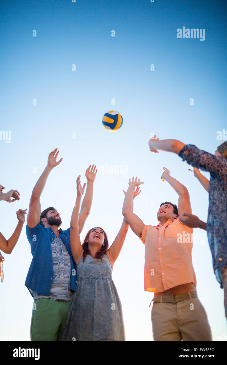 Happy friends throwing volleyball Stock Photo - Alamy