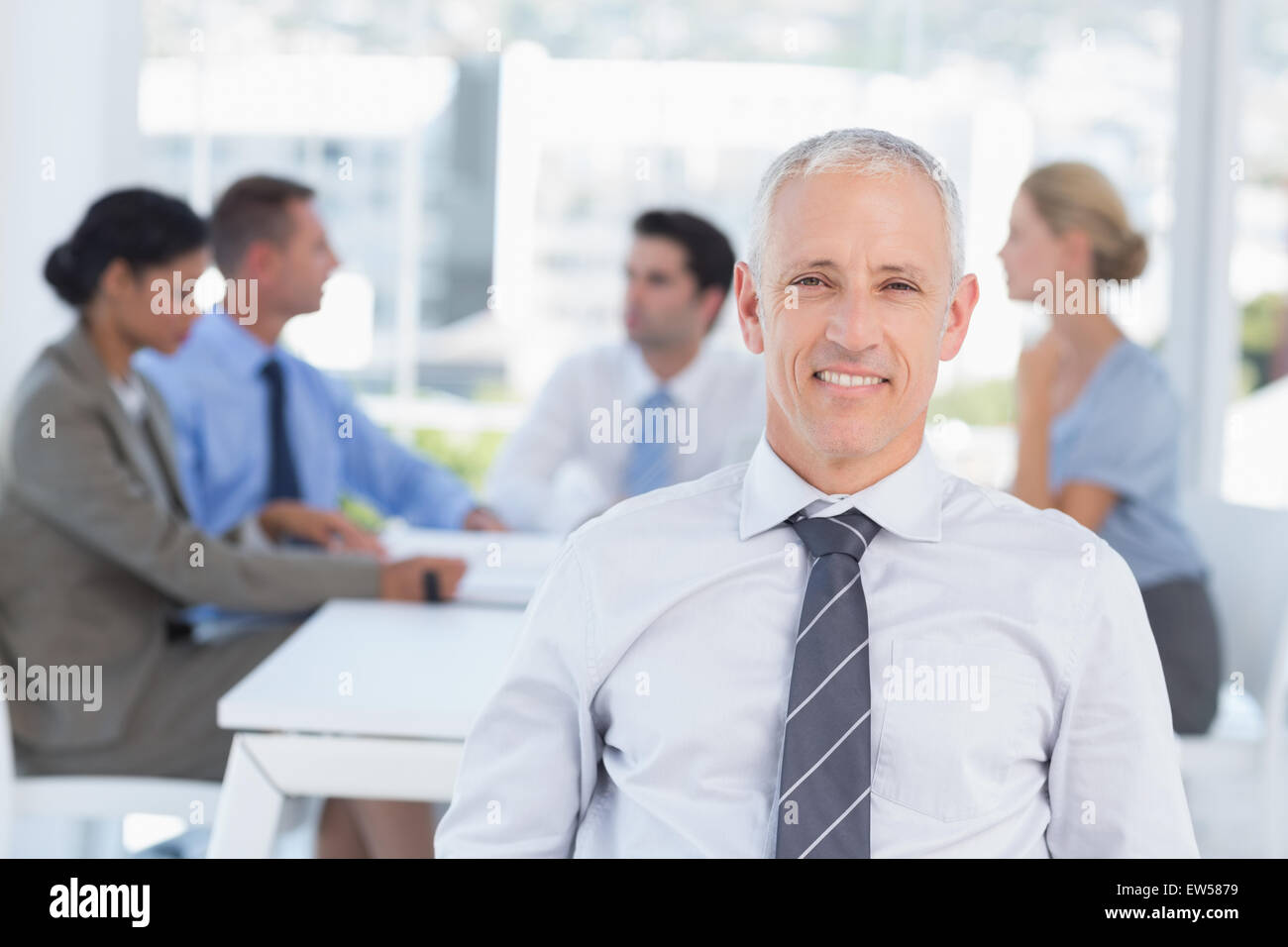 Smiling businessman and his team Stock Photo - Alamy
