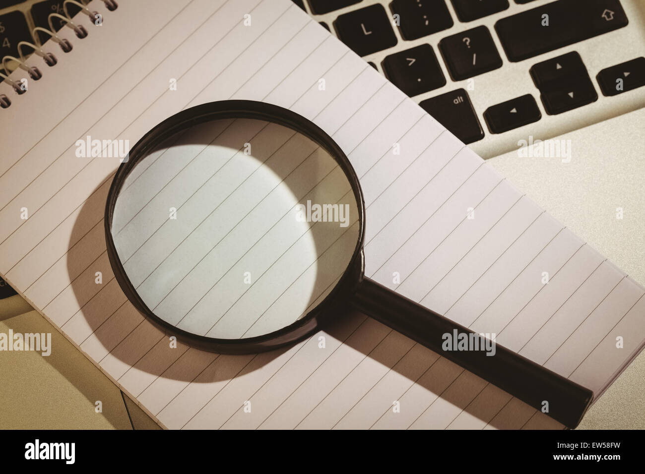 Magnifying glass and notepad on laptop Stock Photo - Alamy