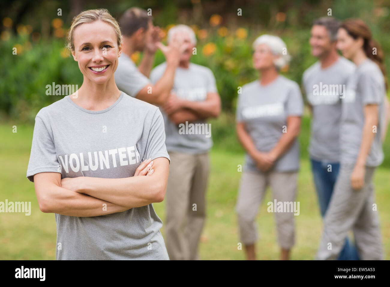 Happy volunteer looking at camera with arms crossed Stock Photo - Alamy
