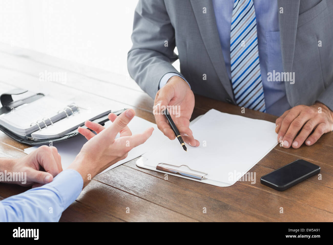 Businessman explaining contract to co worker Stock Photo - Alamy