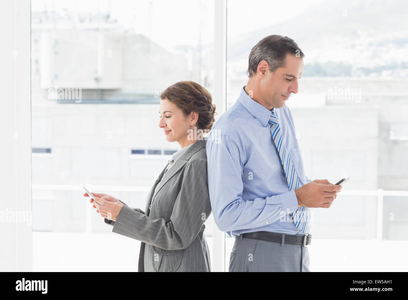 Businesswoman back-to-back with colleague Stock Photo - Alamy