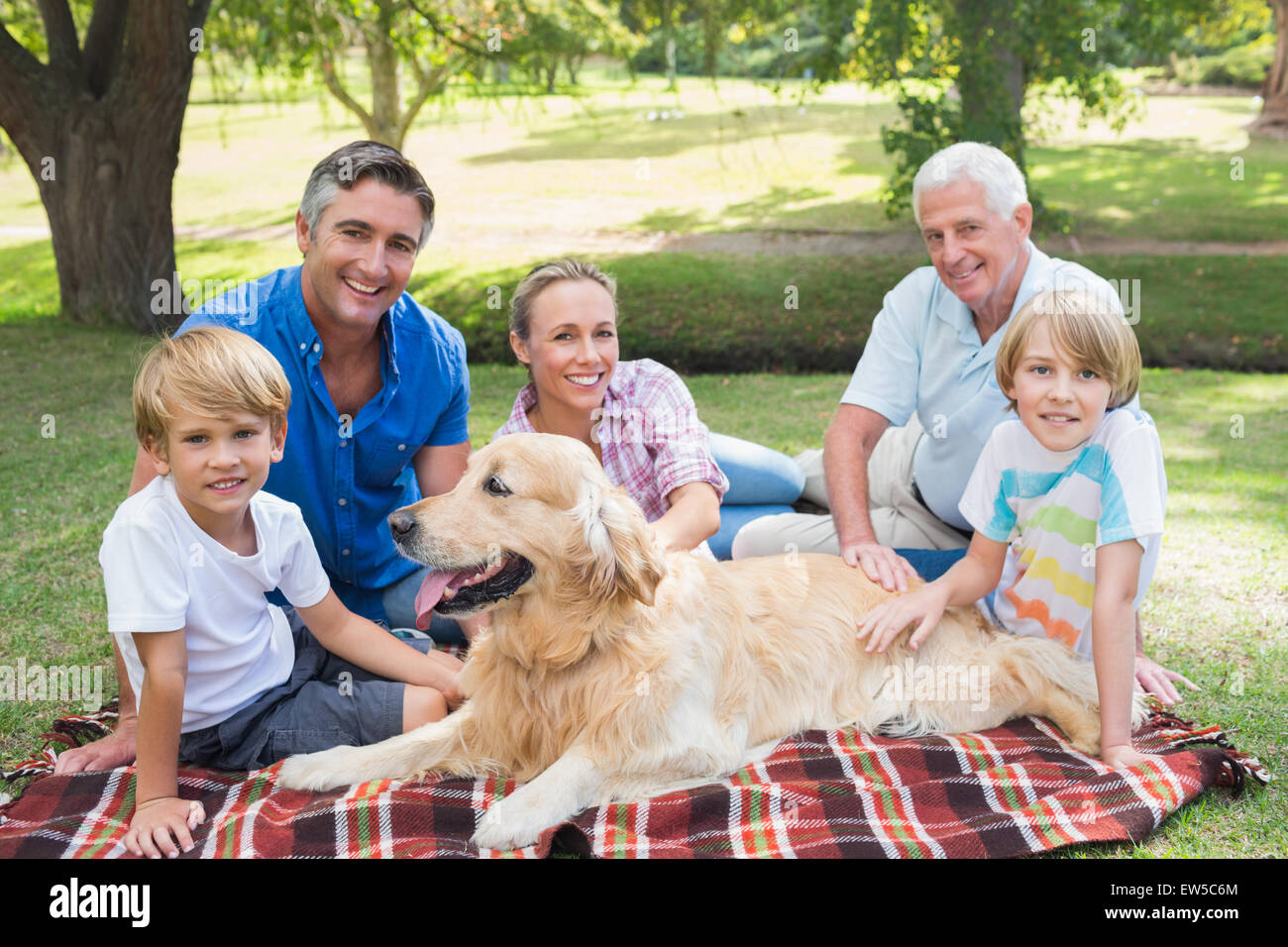Happy family smiling at the camera with their dog Stock Photo - Alamy