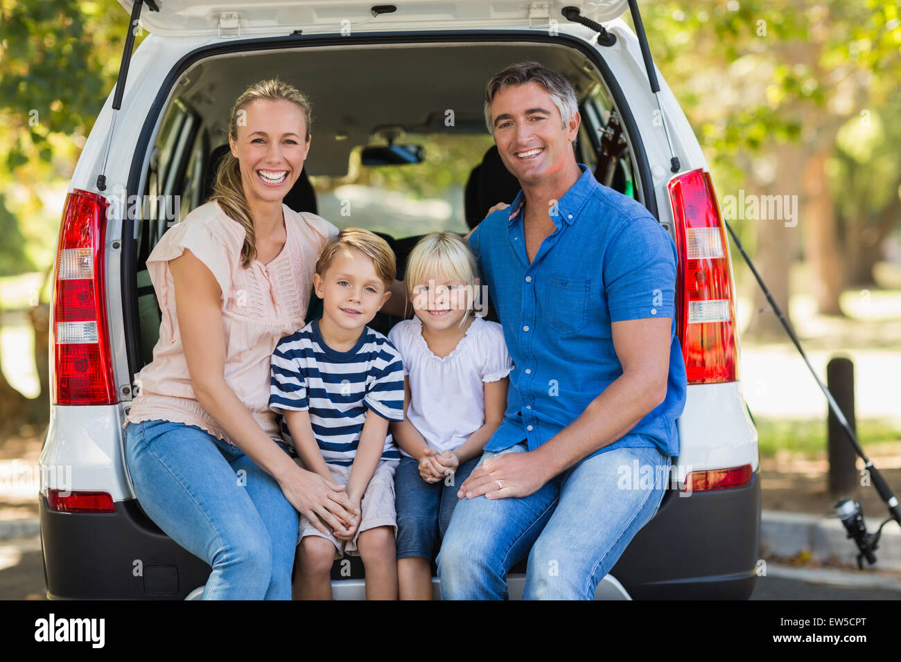 Happy family of four sitting in car trunk Stock Photo - Alamy