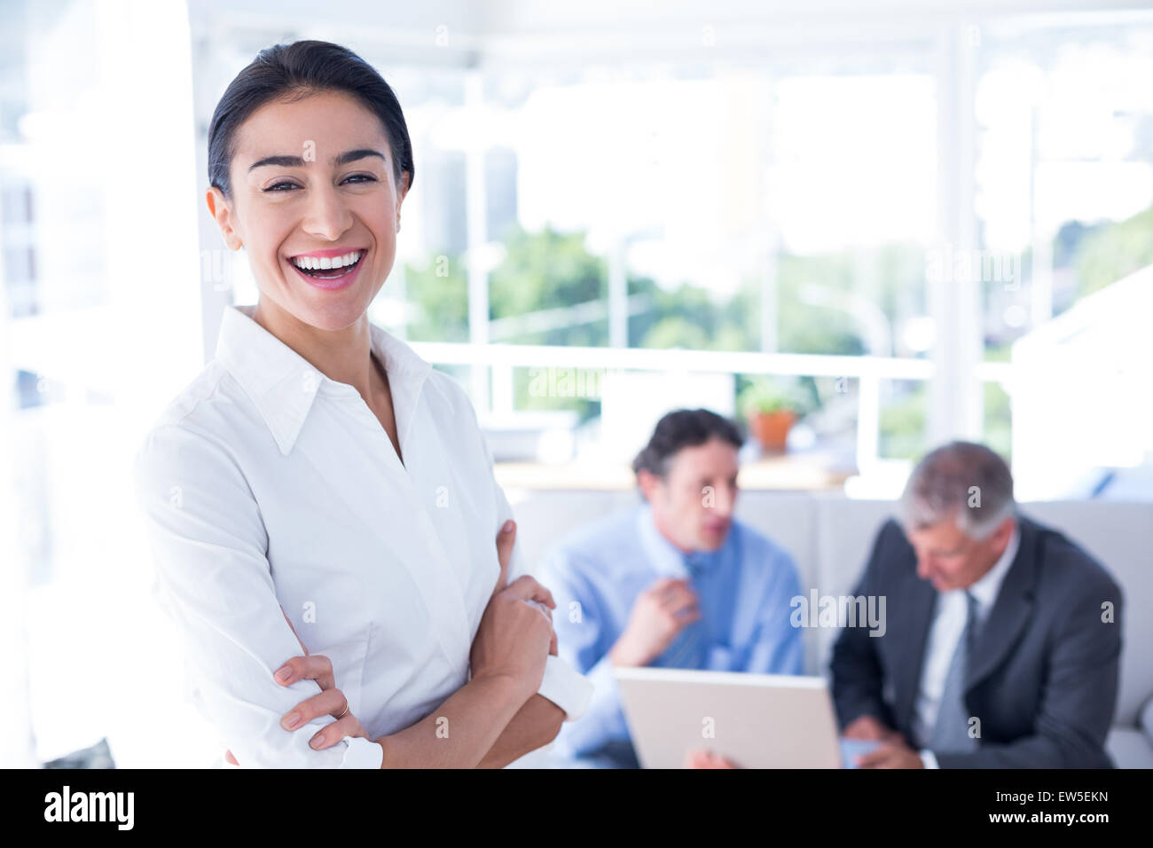 Smiling businesswoman with colleagues behind Stock Photo - Alamy
