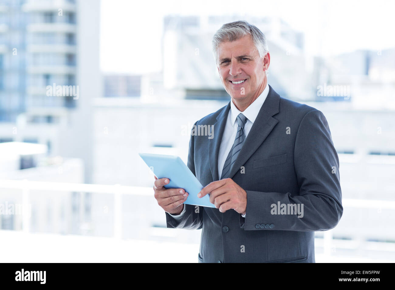 Smiling businessman using his tablet Stock Photo - Alamy