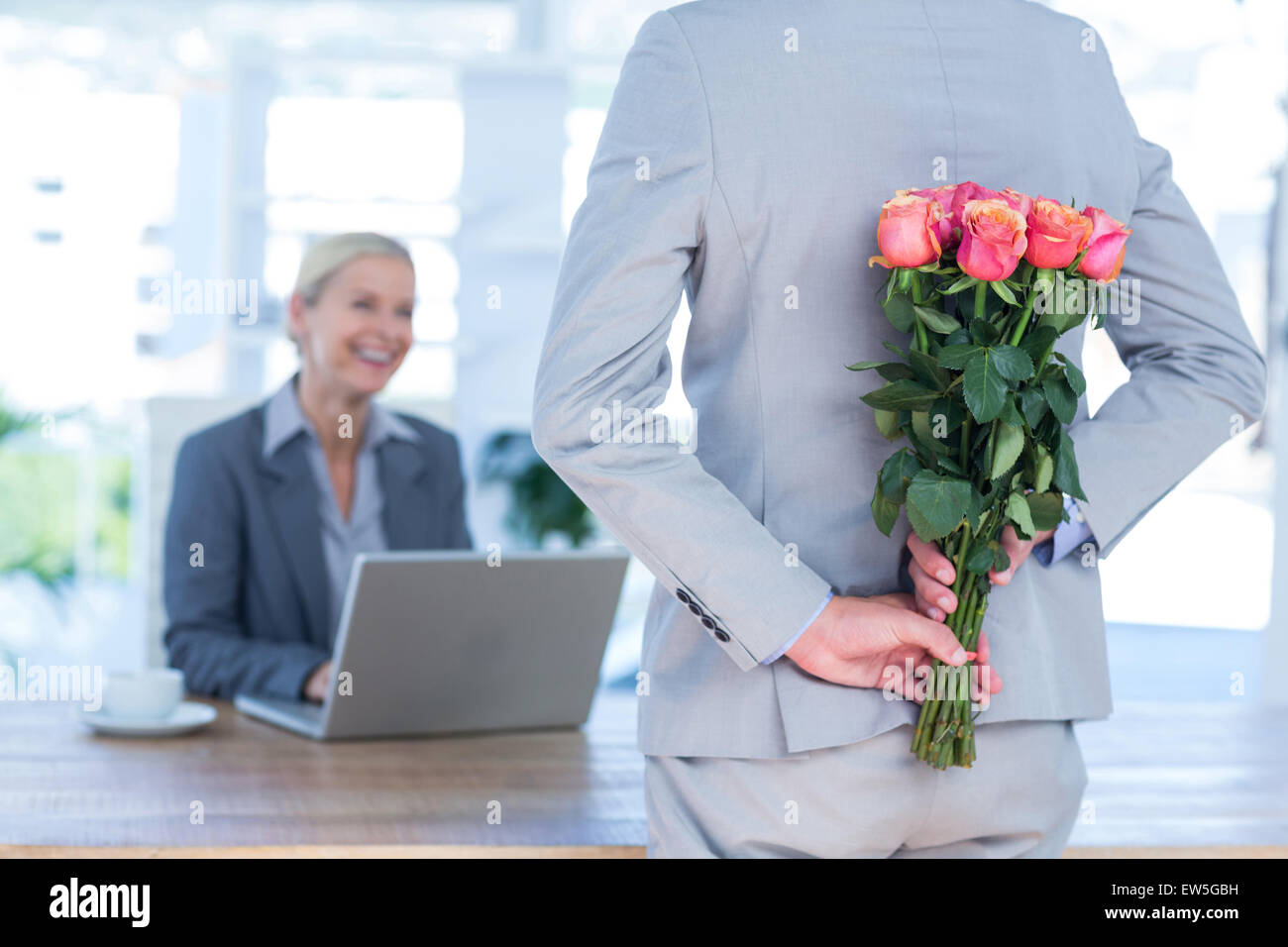 Businessman hiding flowers behind back for colleague Stock Photo - Alamy
