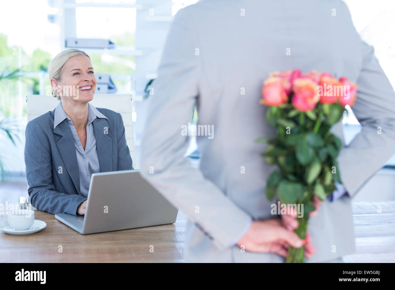Businessman hiding flowers behind back for colleague Stock Photo - Alamy
