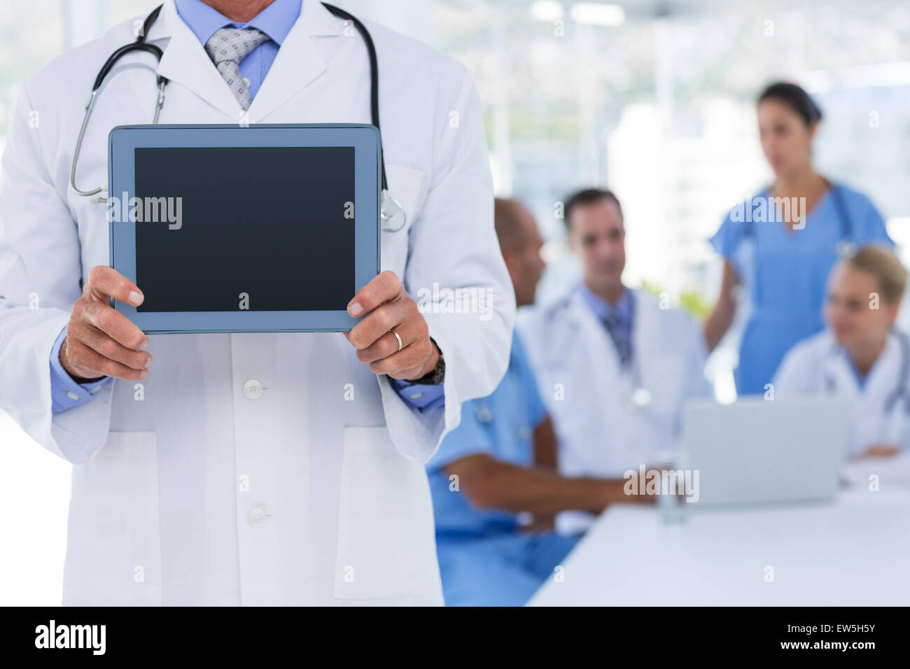 Doctor holding tablet computer while his colleagues works Stock Photo ...