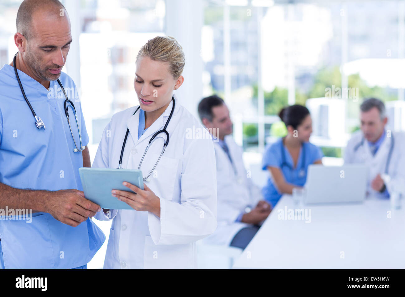 Two doctors holding clipboard while their colleagues working Stock ...
