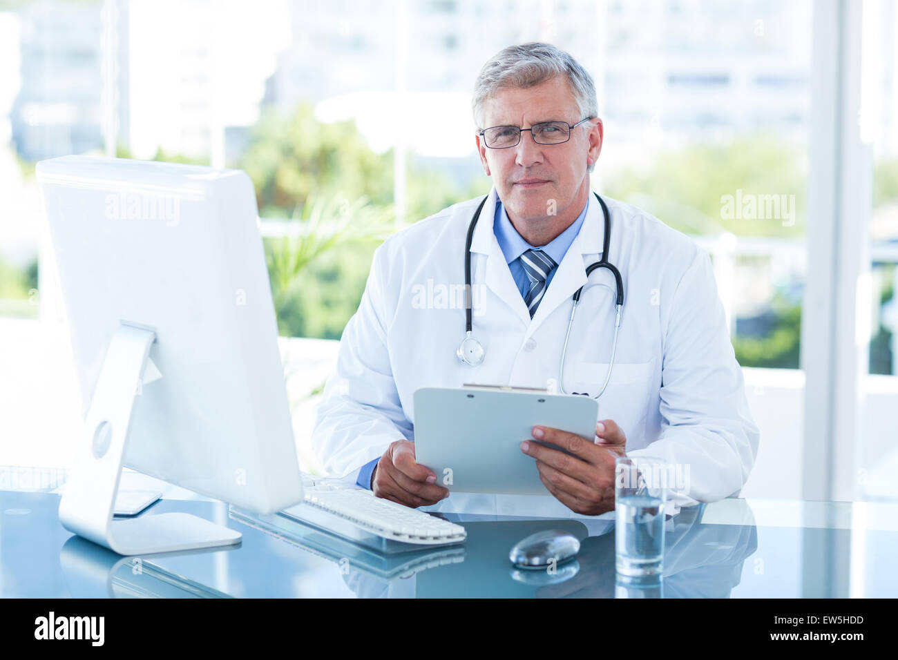 Smiling doctor working on computer at his desk Stock Photo - Alamy