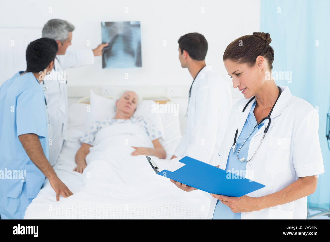 Report reading with colleagues and patient behind Stock Photo - Alamy