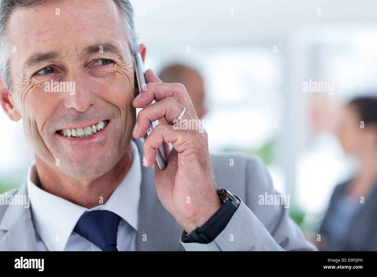 businessman using her phone with two colleague behind him Stock Photo ...