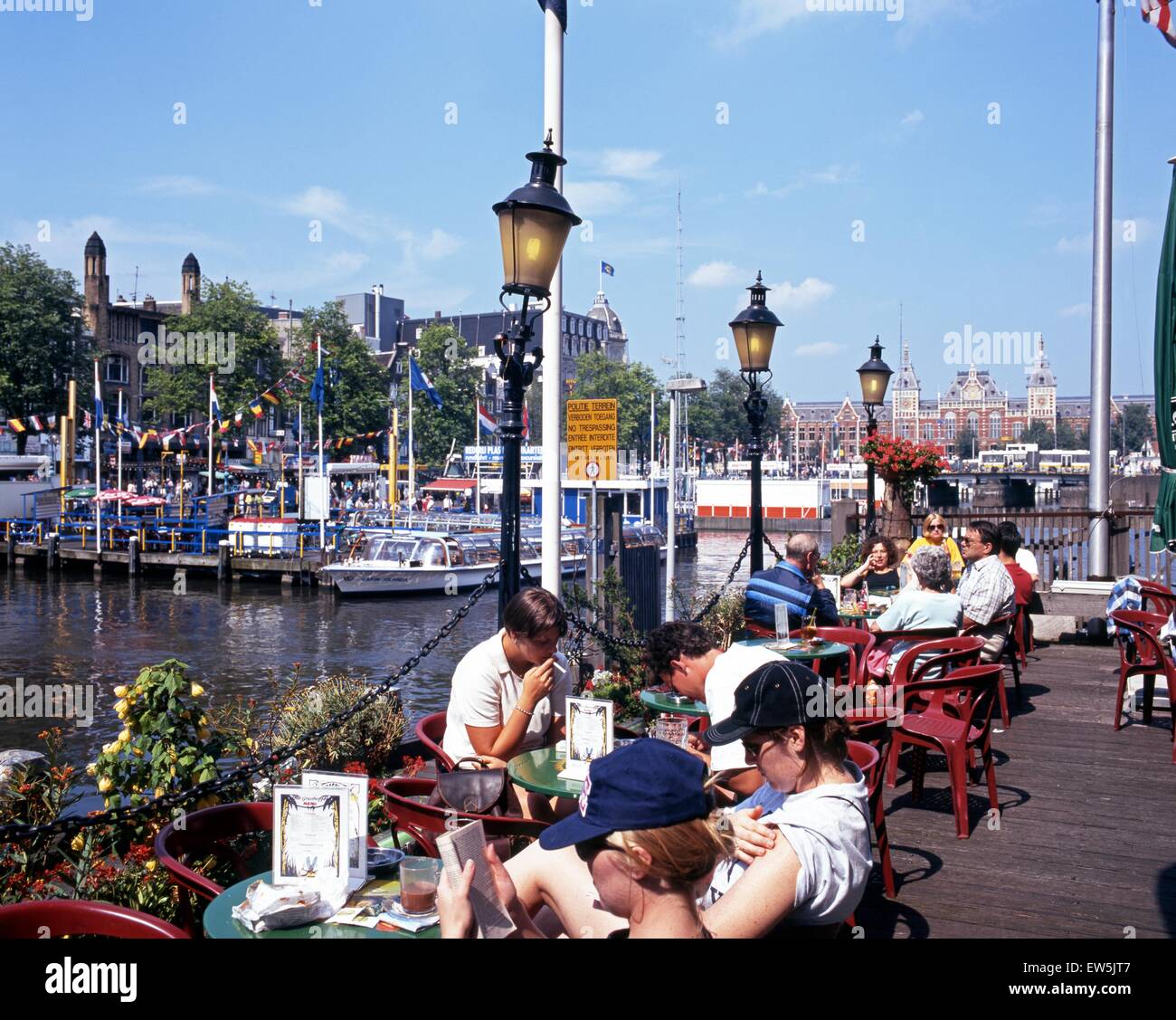People relaxing at a pavement cafe along Damrak, Amsterdam, Holland ...