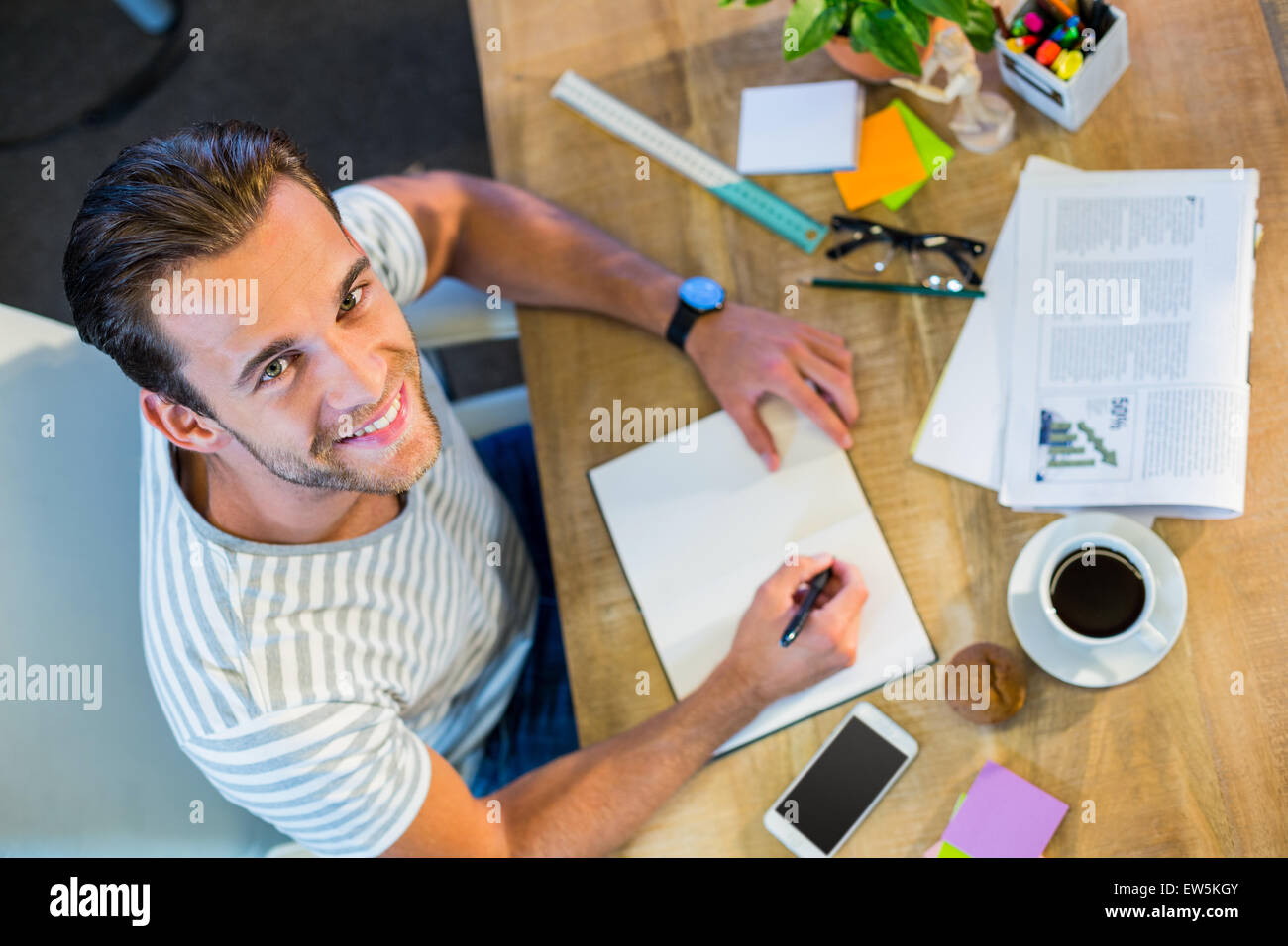 Smiling casual businessman writing in notepad Stock Photo - Alamy