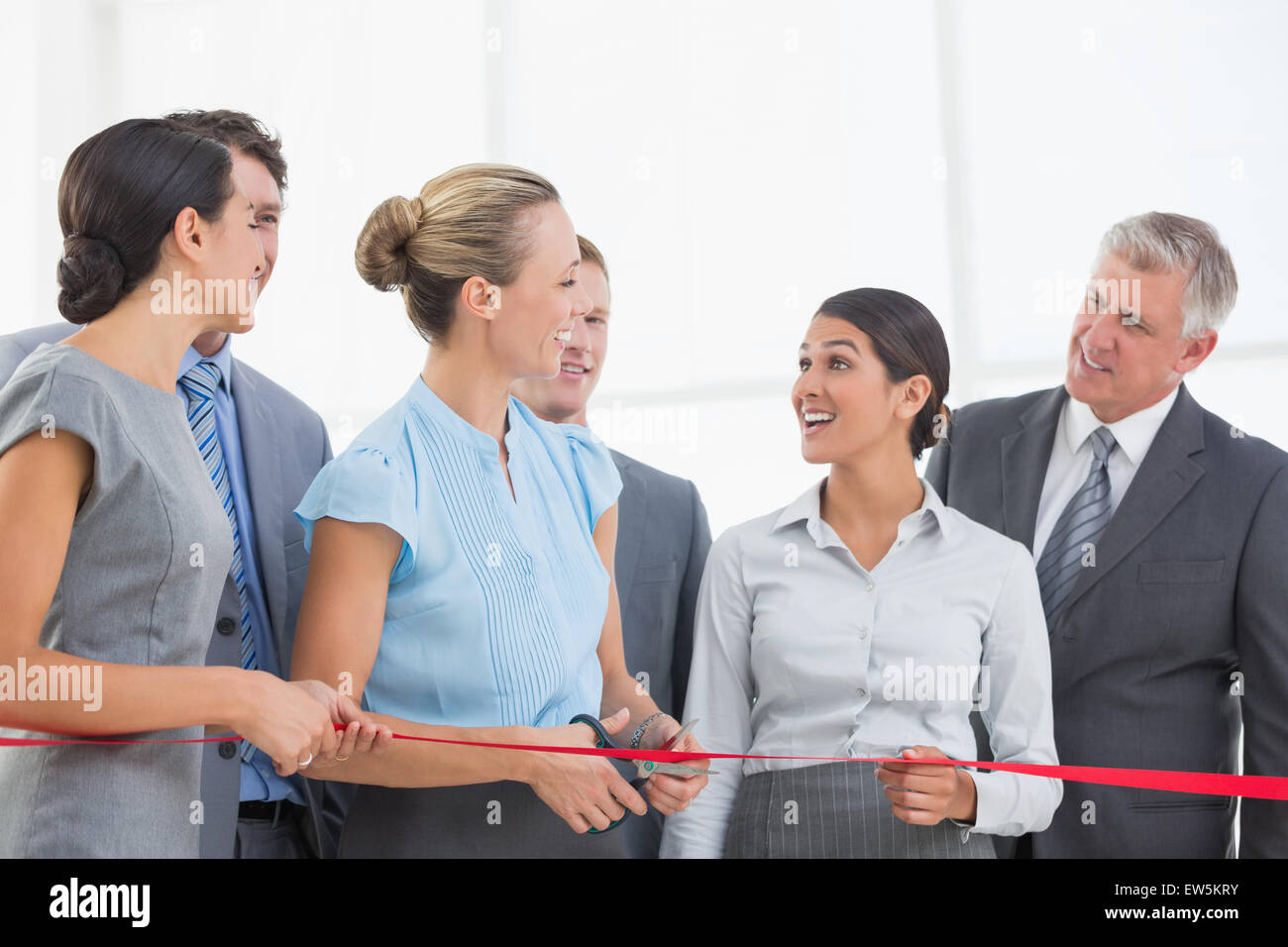 Happy business team cutting red ribbon Stock Photo - Alamy